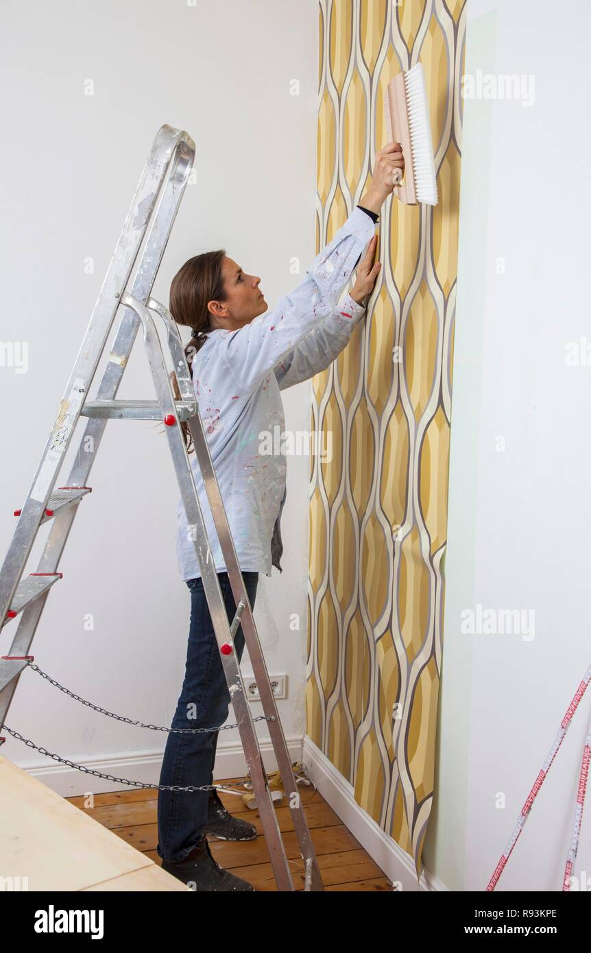 Young woman wallpapering a wall Stock Photo - Alamy