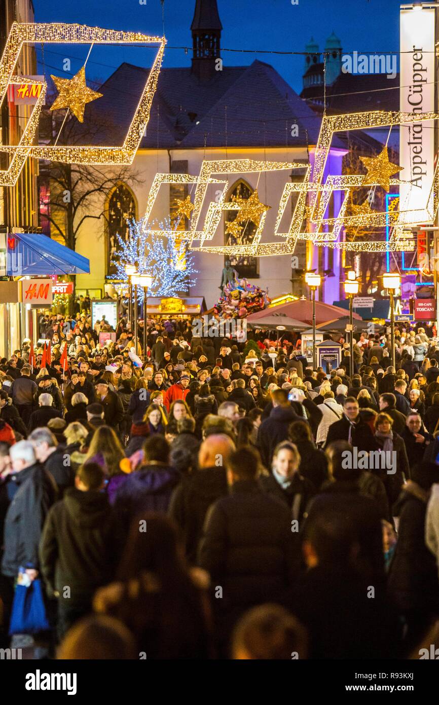 Crowds thronging between stores and Christmas market stalls, pedestrian ...
