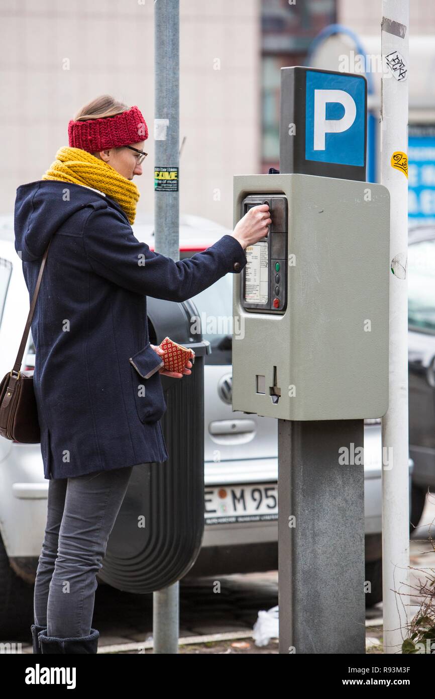 Woman purchasing a parking ticket from a parking ticket vending machine ...