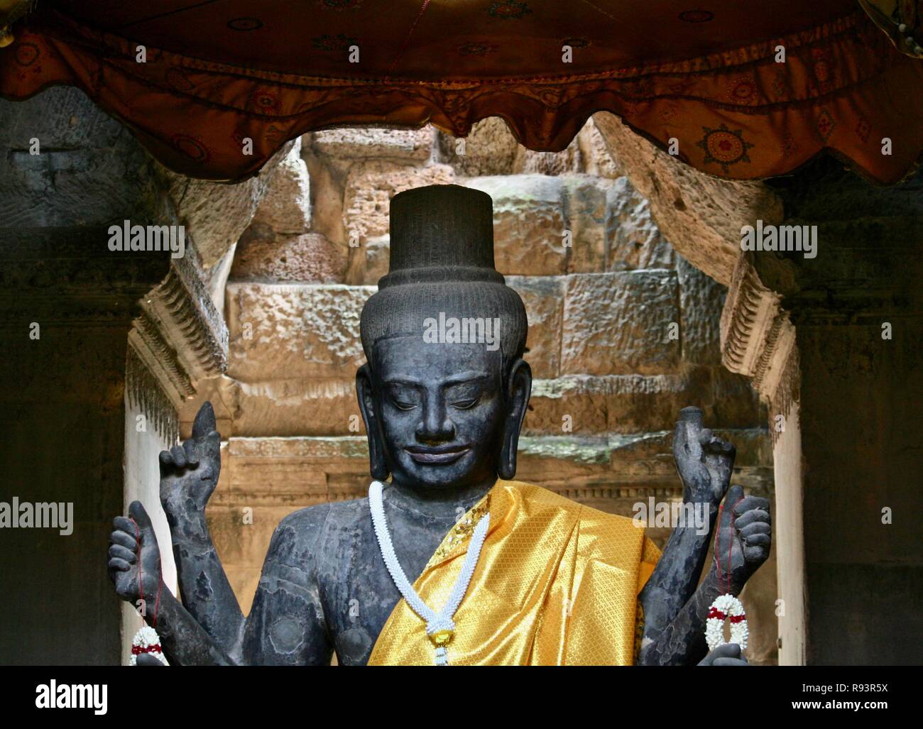 Multi armed buddha with golden sash and white flowers in Cambodia Stock ...