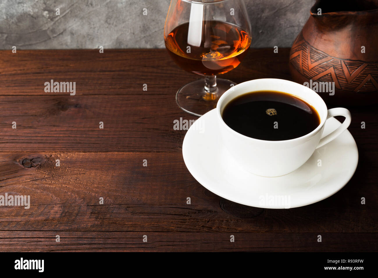 Coffee in white cup with cognac and clay cezve on wooden background ...