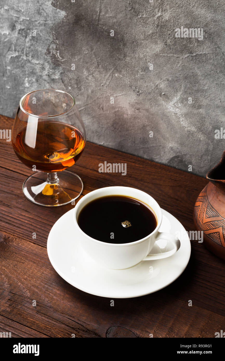 Coffee in white cup with cognac and clay cezve on wooden background ...
