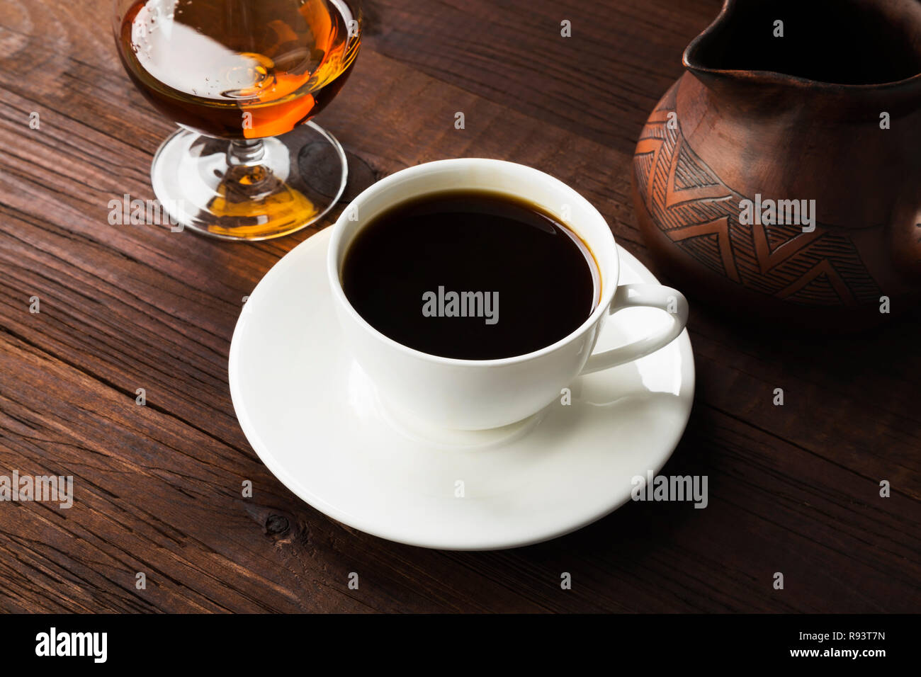 Coffee in white cup with cognac and clay cezve on wooden background ...