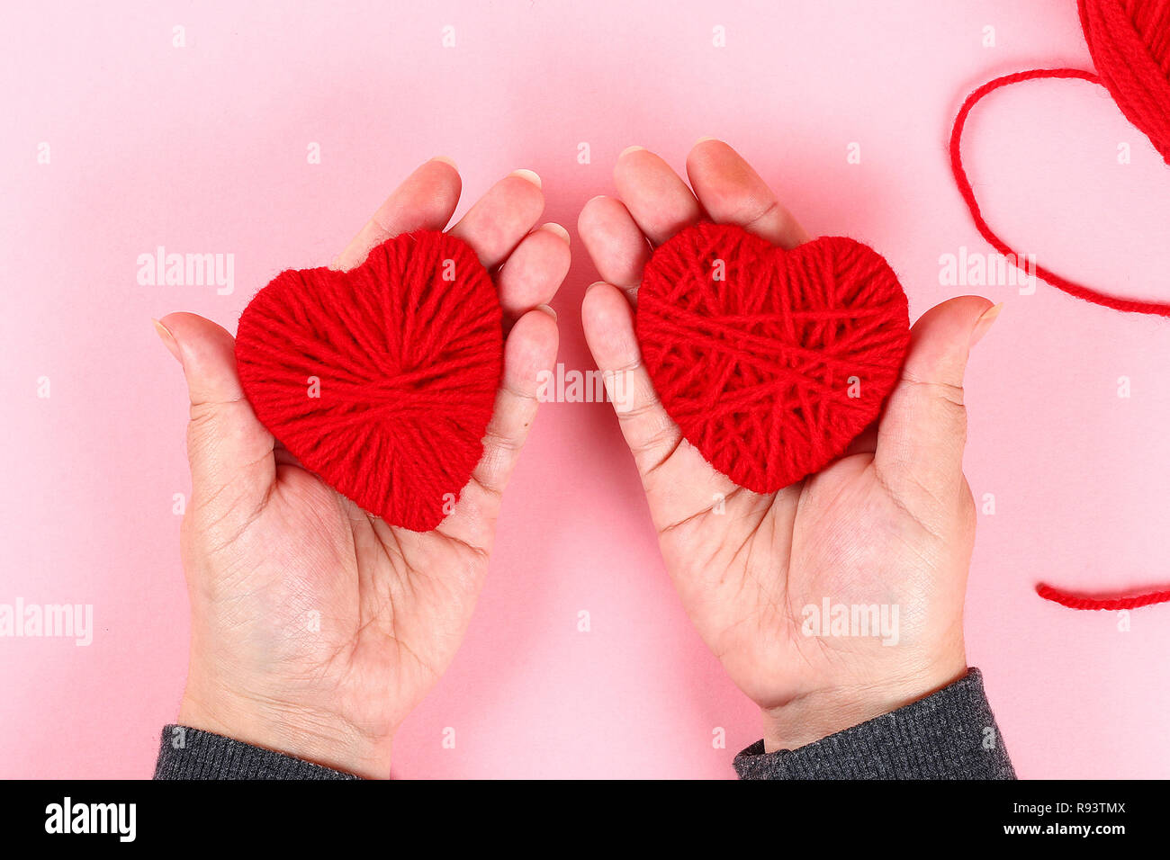 Red handmade diy hearts made of cardboard, yarn on a pink background ...