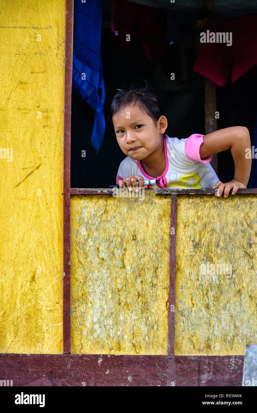 Young Indigenous child climbing through the Window of her home in ...