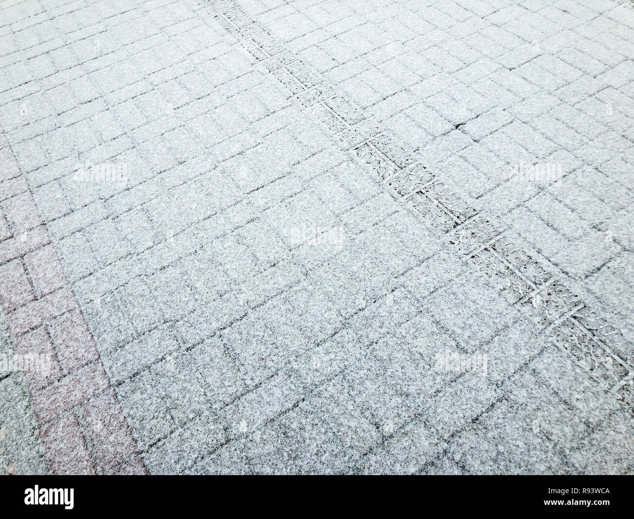 snow covered paving tiles after snowfall. winter background with tire ...