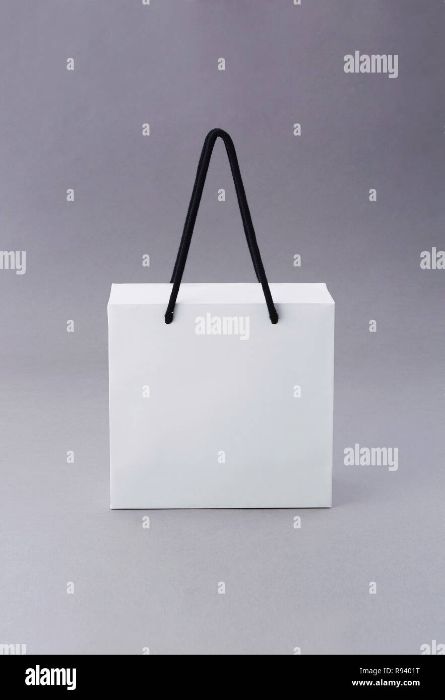 a white paper bag in front of a gray background Stock Photo - Alamy
