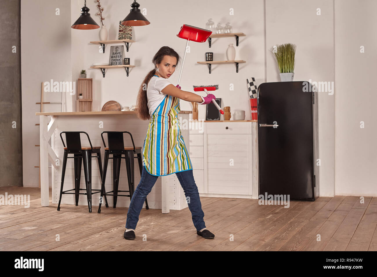 Funny picture of brunette holding scoop and broom in hands. She ...