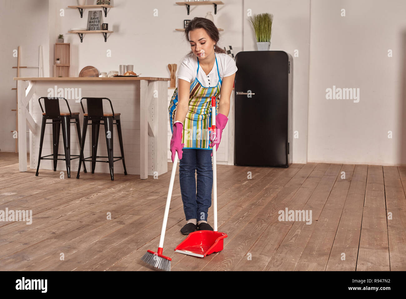Cleaning concept. Young woman sweeping floor on the kitchen Stock Photo ...