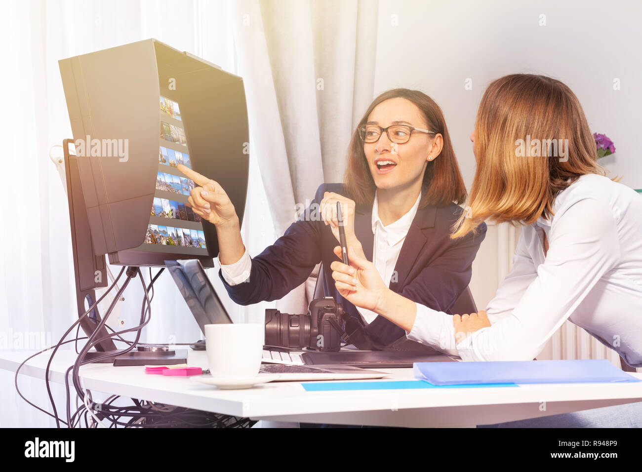 Portrait of female photographer and client pointing to the computer ...