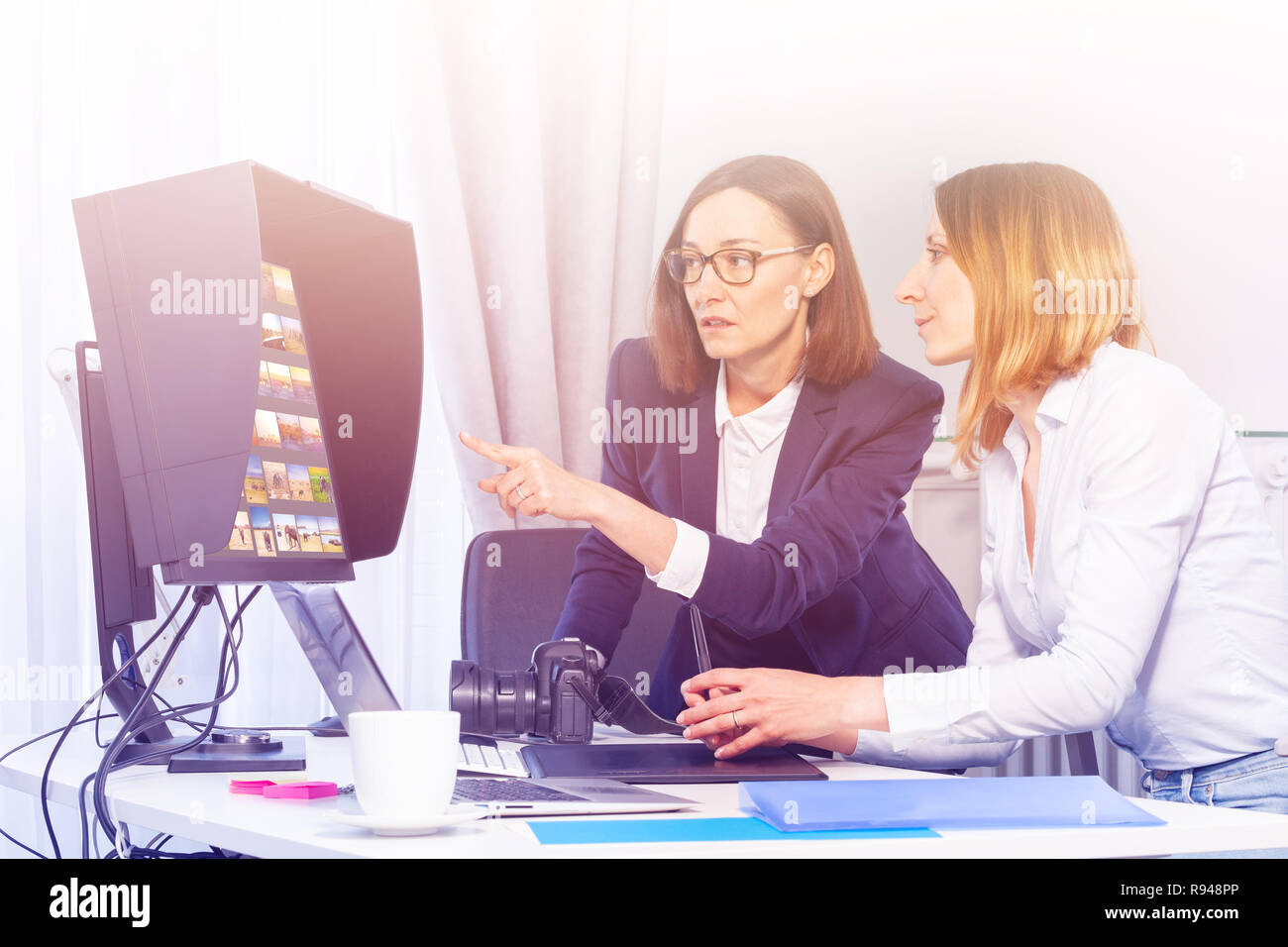 Portrait of female photographer and client working with computer ...
