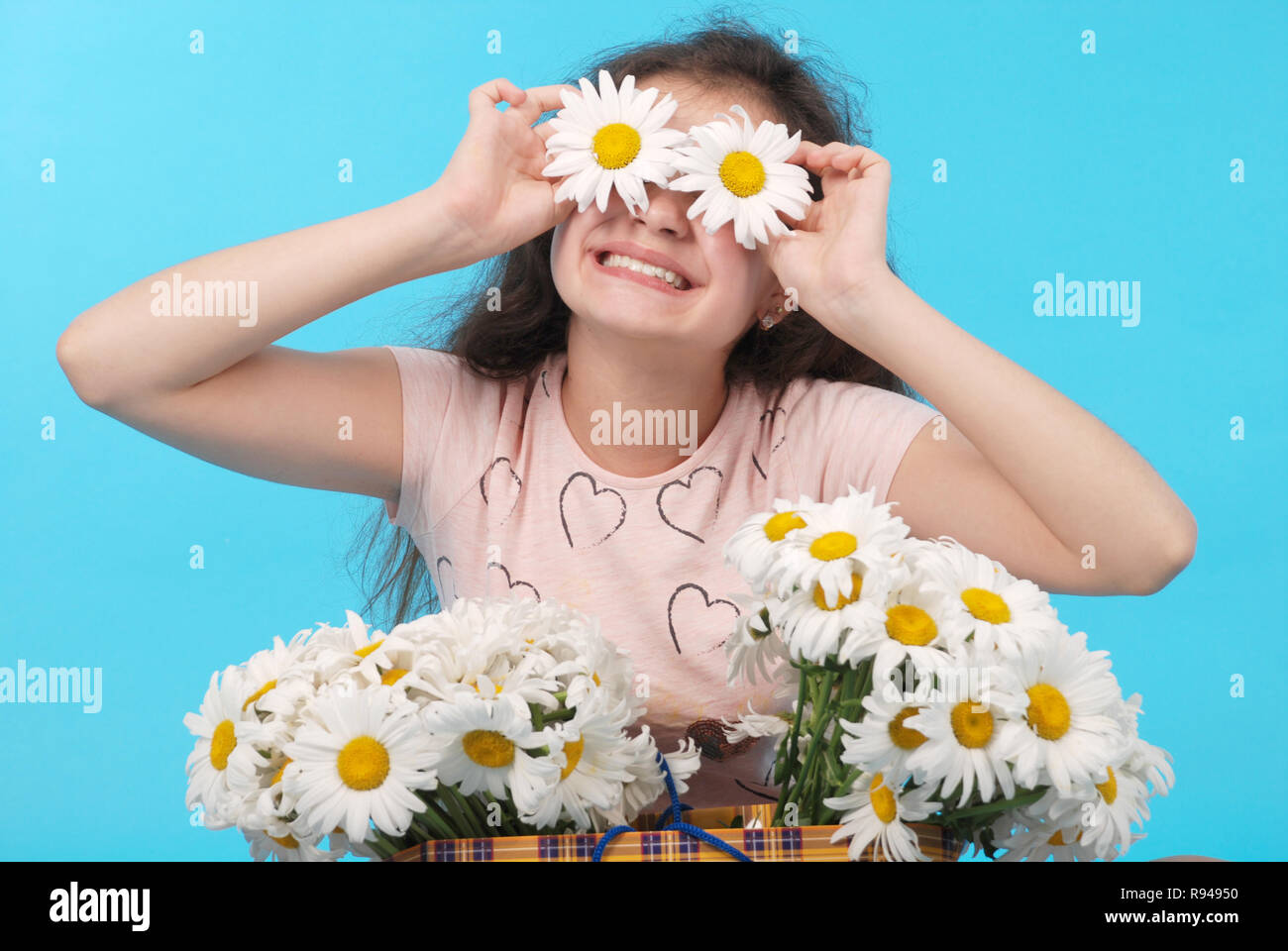 Beautiful young girl with daisy eyes on blue background Stock Photo - Alamy