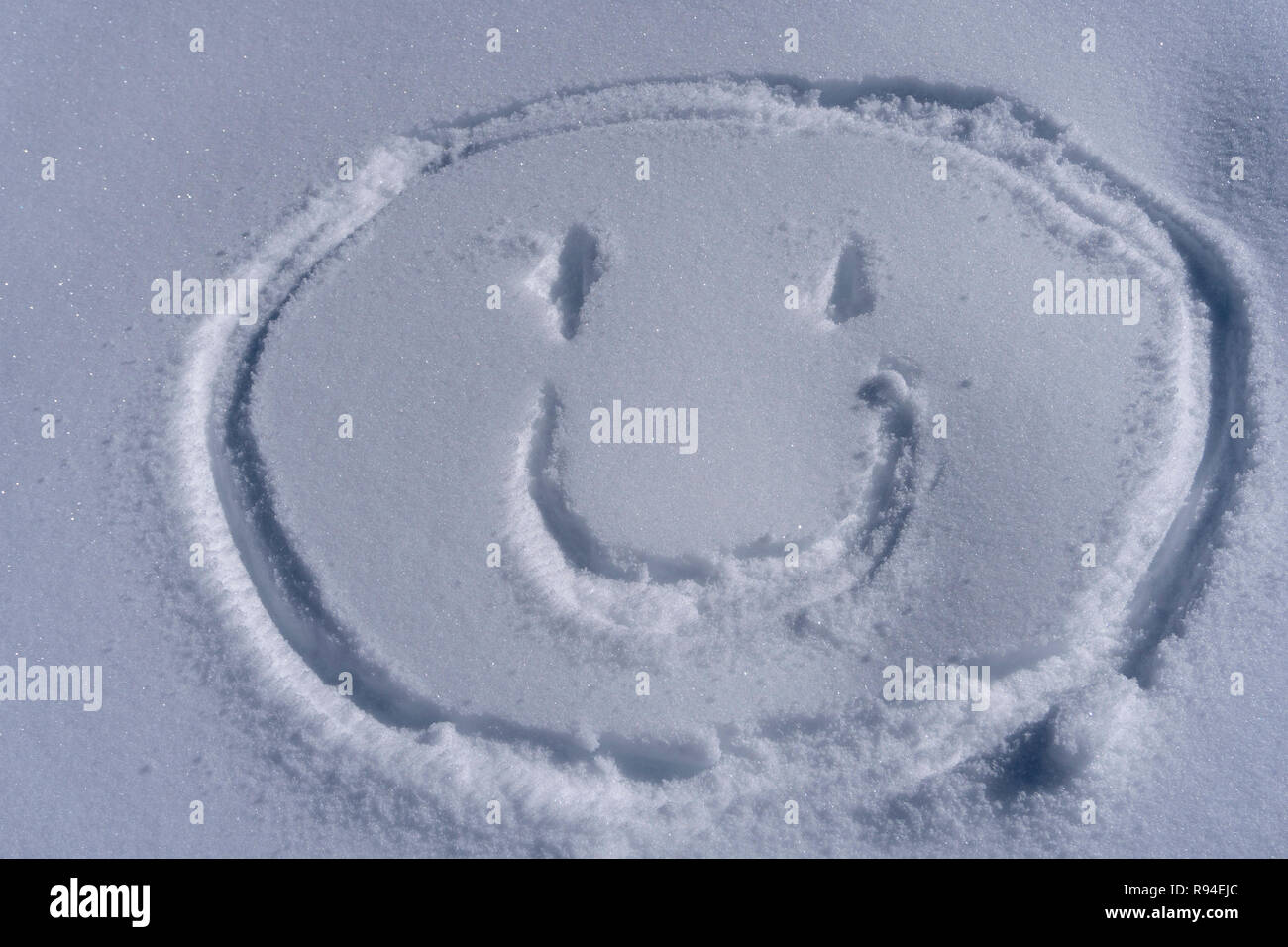 smile face emoticon writing on the snow detail Stock Photo - Alamy