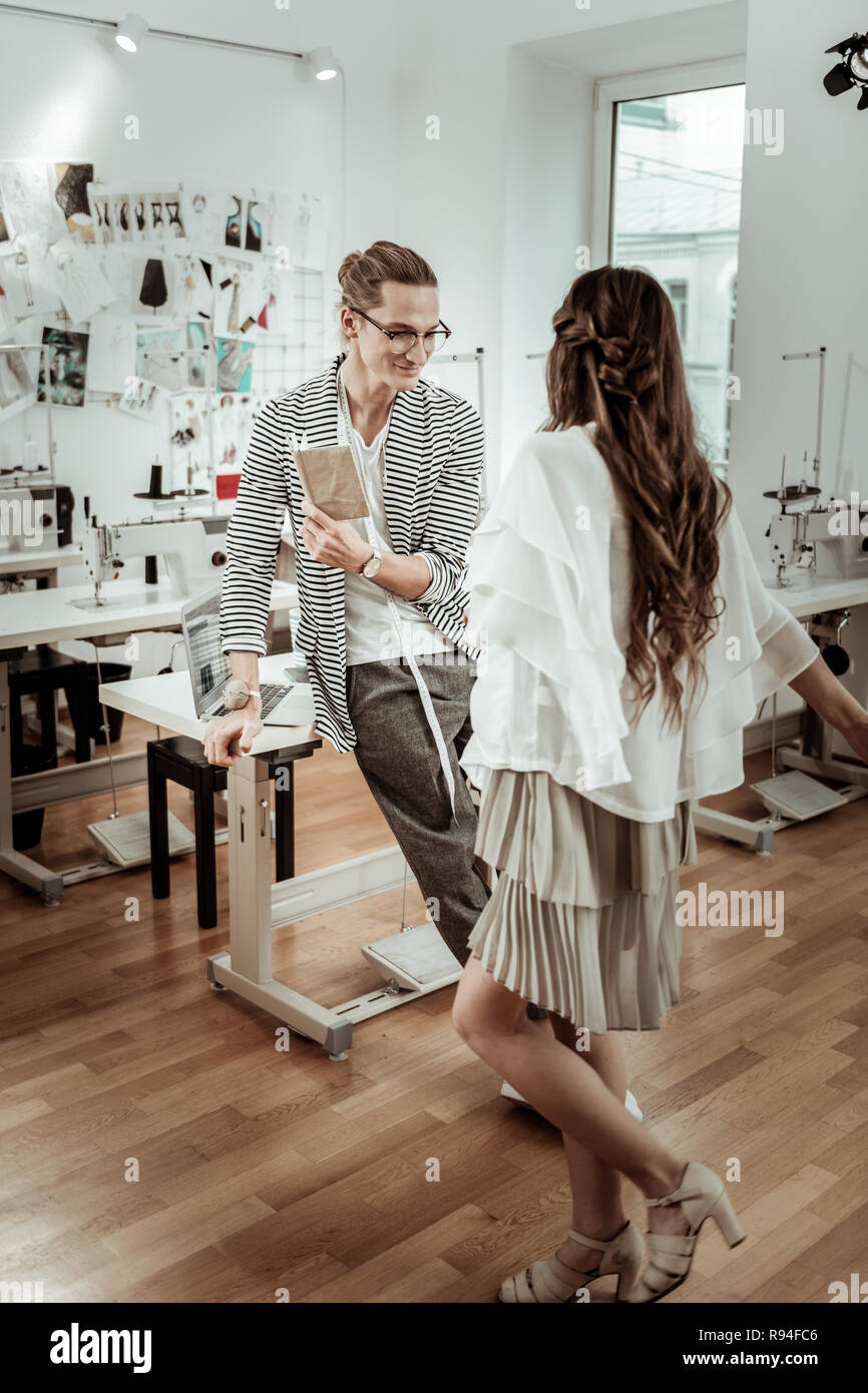 Pretty young long-haired model in a beige dress dancing in the studio ...