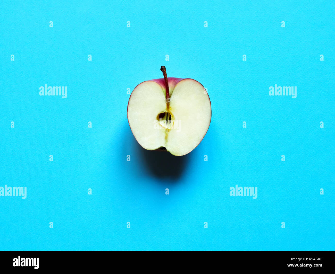 Apple fruit sliced by half isolated in studio over a light blue ...