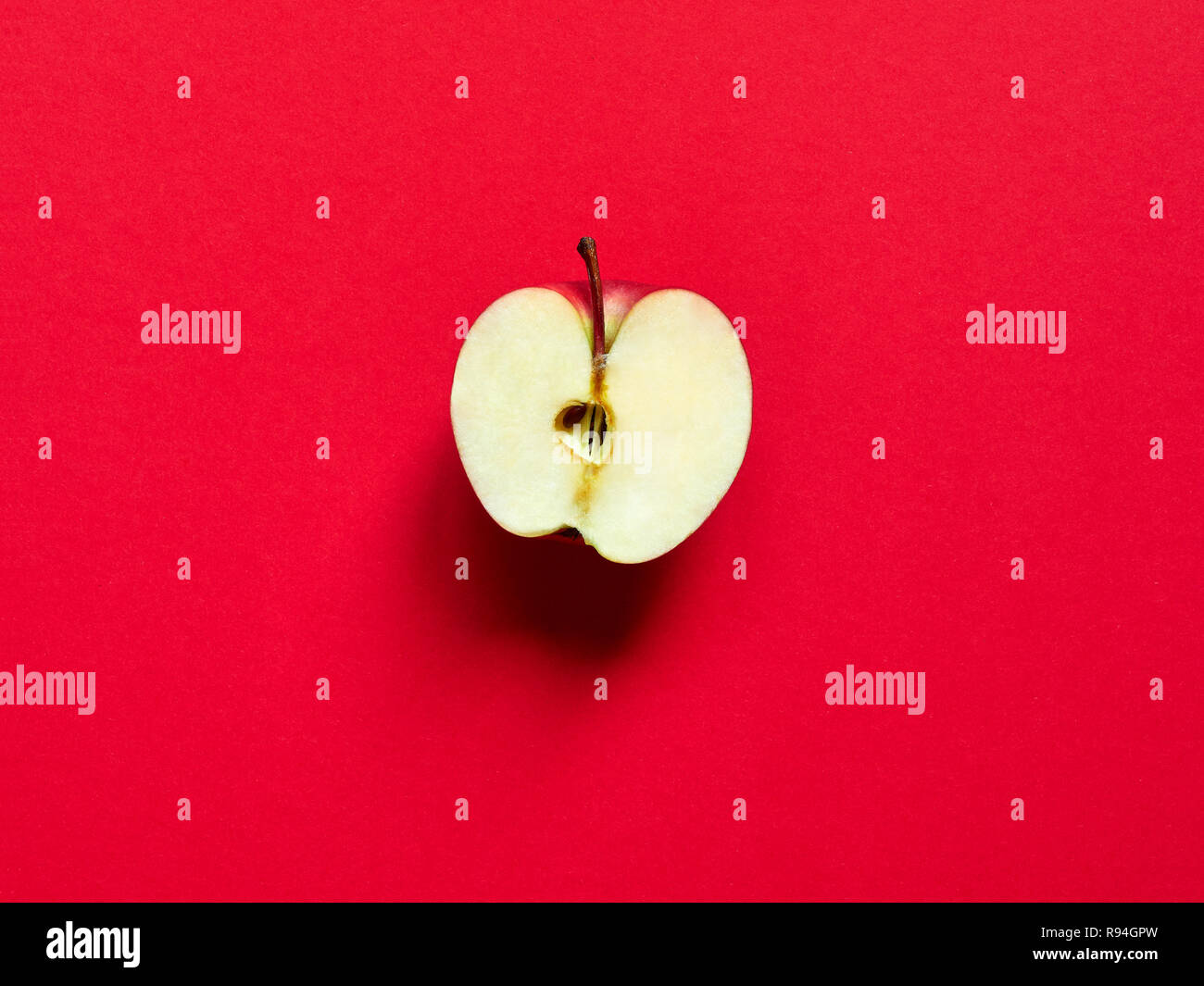 Apple fruit sliced by half isolated in studio over a vivid red ...