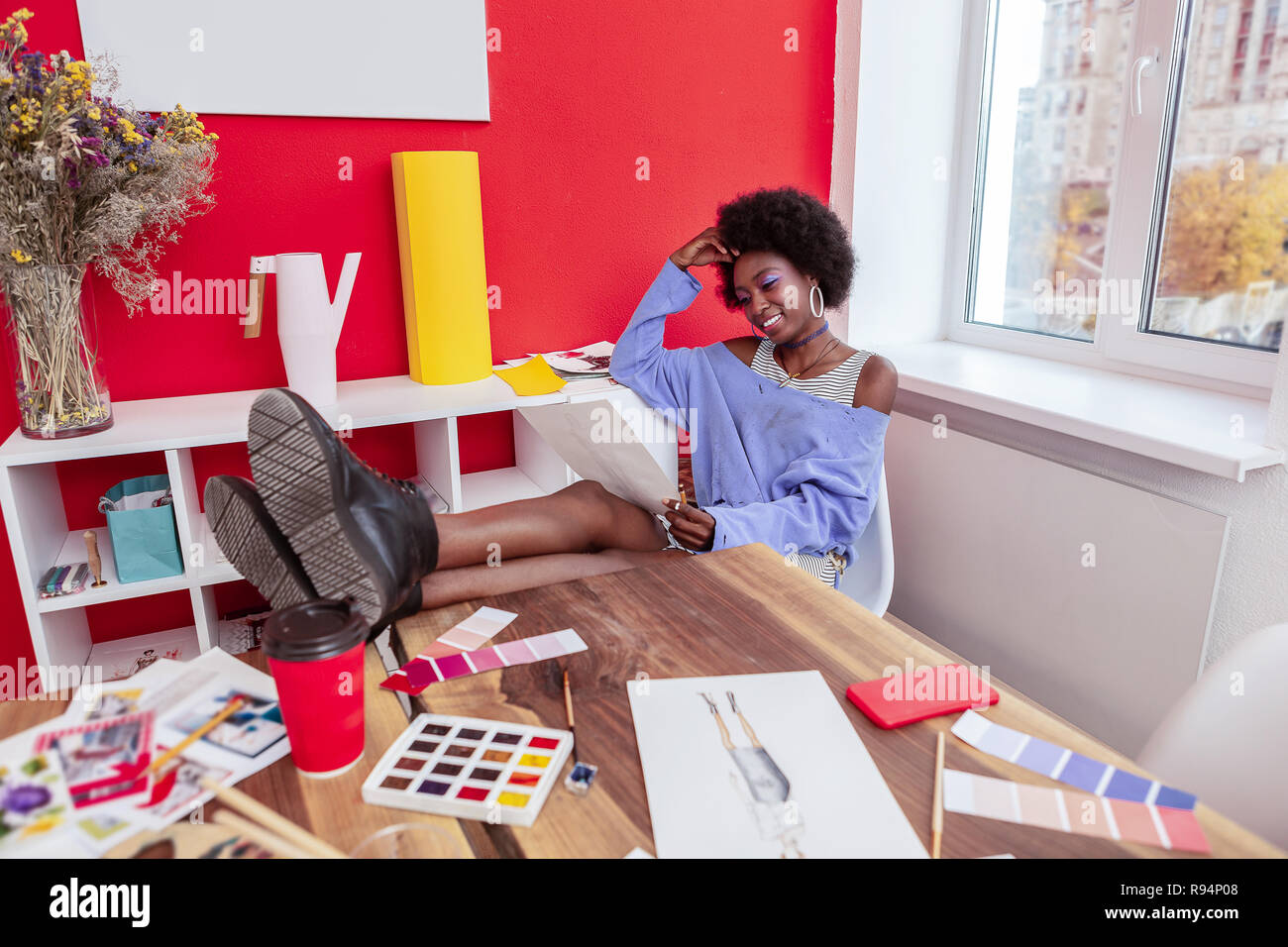 Fashion designer putting her legs on the table while looking at ...