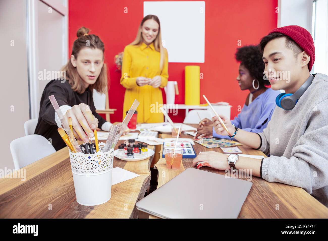 Blonde-haired male designer taking pencil while drawing something Stock ...
