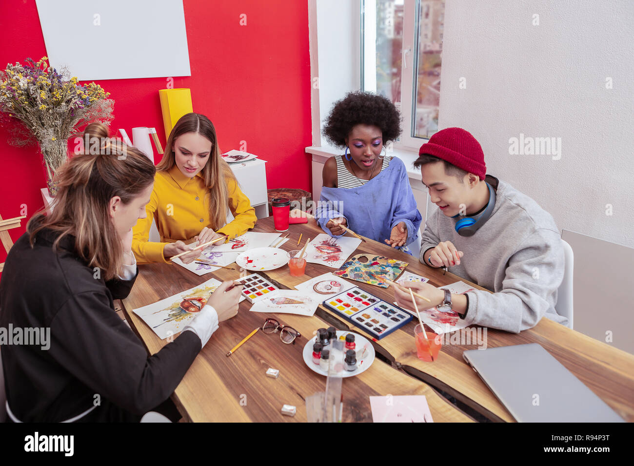 Four promising art students using paints while drawing Stock Photo - Alamy