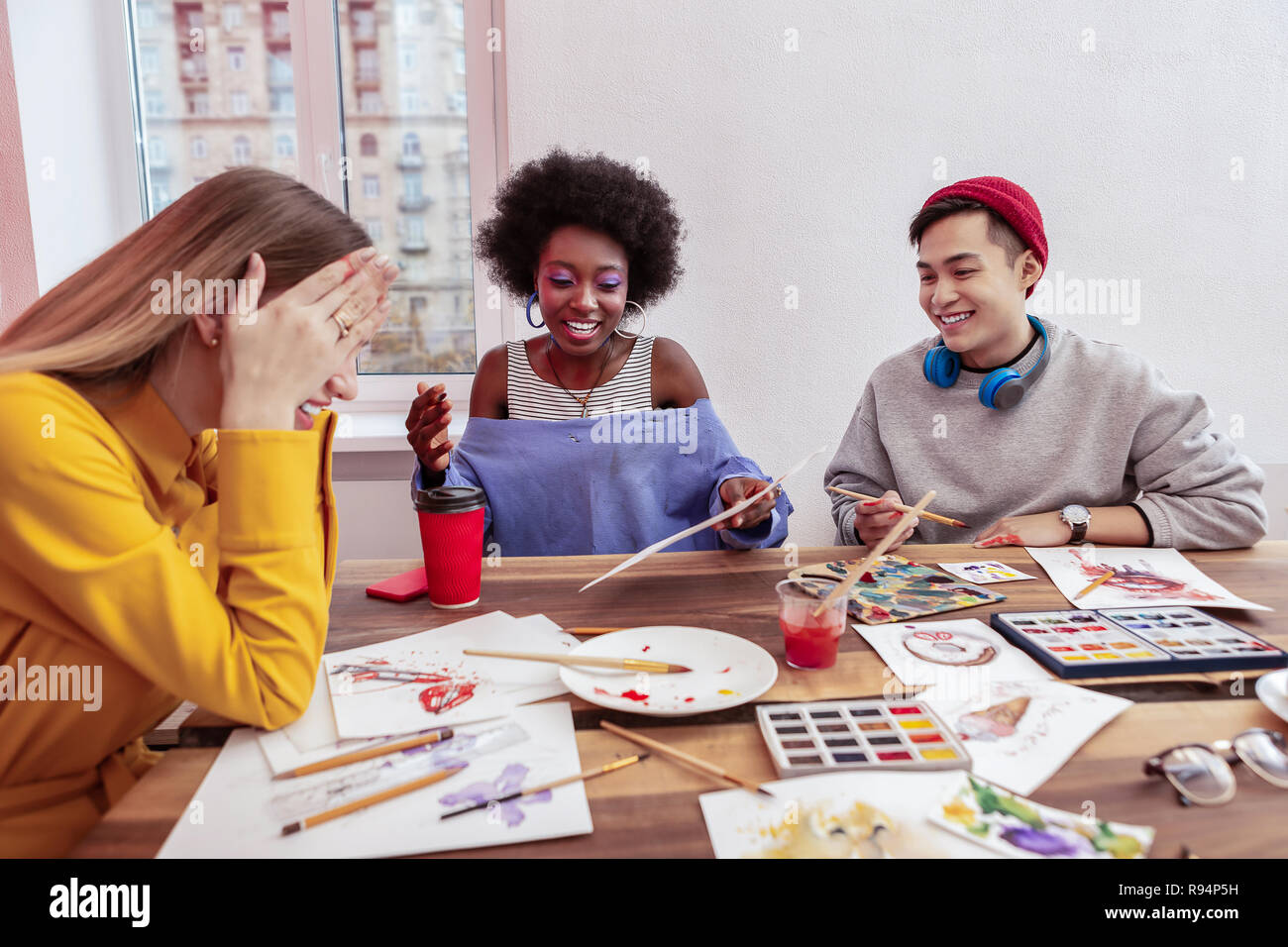 Three young artists laughing while having a little break Stock Photo ...
