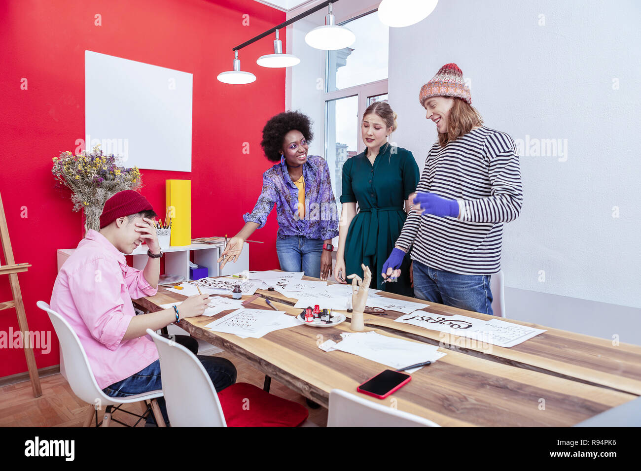 Three young creative managers laughing at their colleague Stock Photo ...