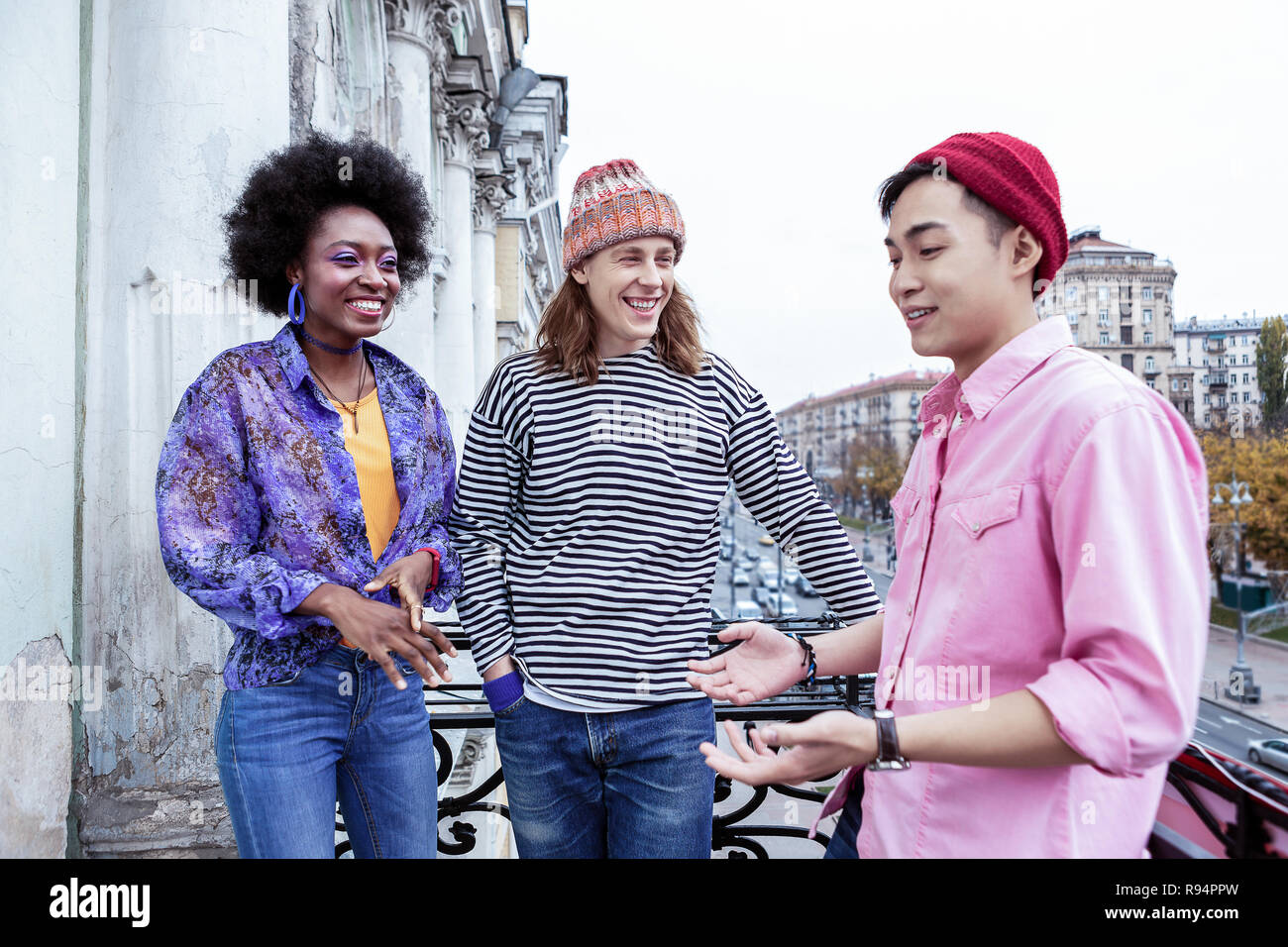 Handsome dark-haired man wearing red hat telling jokes to his friends ...