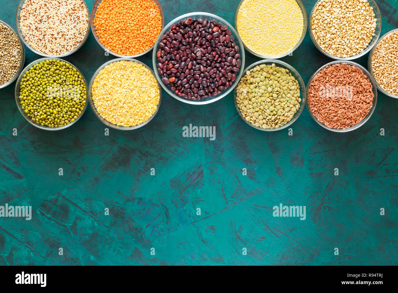 Flat lay glass bowls with superfoods on textured emerald background ...