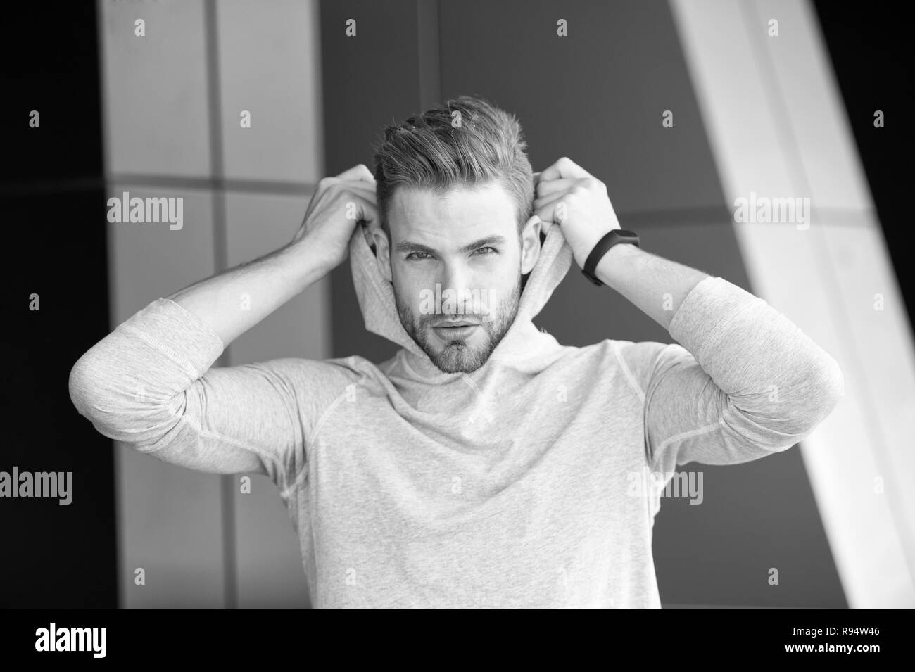 Guy bearded and attractive puts on hood. Man with bristle on serious ...