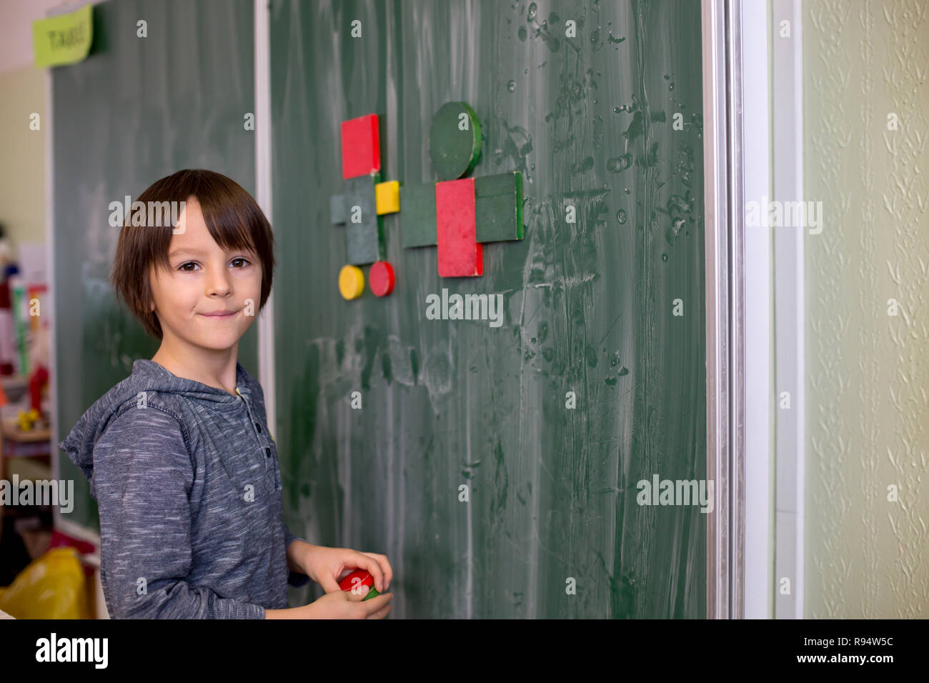 First grade child, learning math, shapes and colors at school, standing ...
