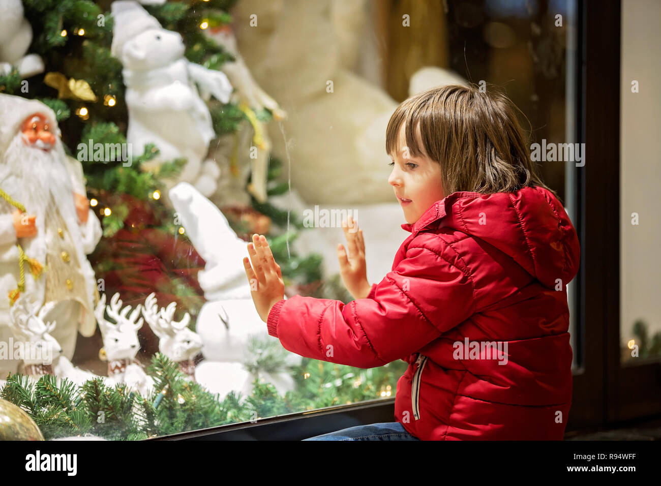 Beautiful little child, boy, watching Christmas decoration with toys in ...