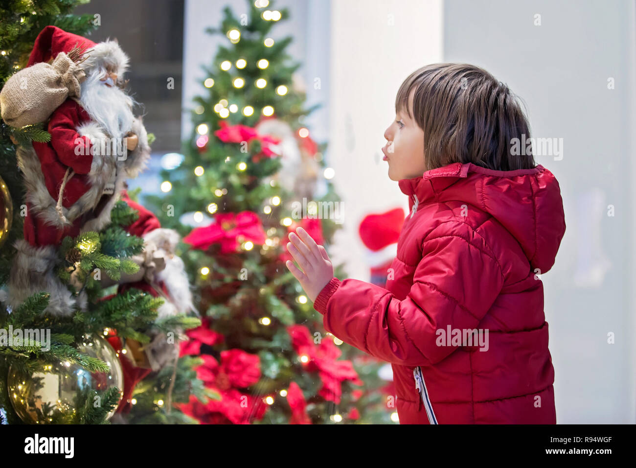 Beautiful little child, boy, watching Christmas decoration with toys in ...