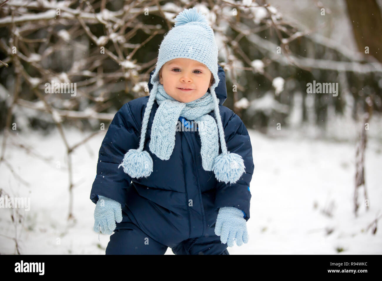 Cute little toddler boy, playing outdoors with snow on a winter day ...
