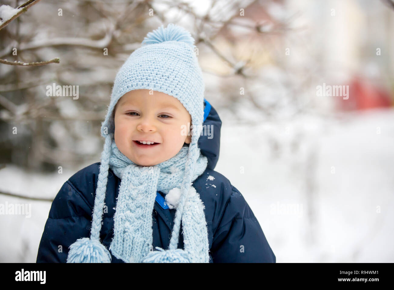 Cute little toddler boy, playing outdoors with snow on a winter day ...