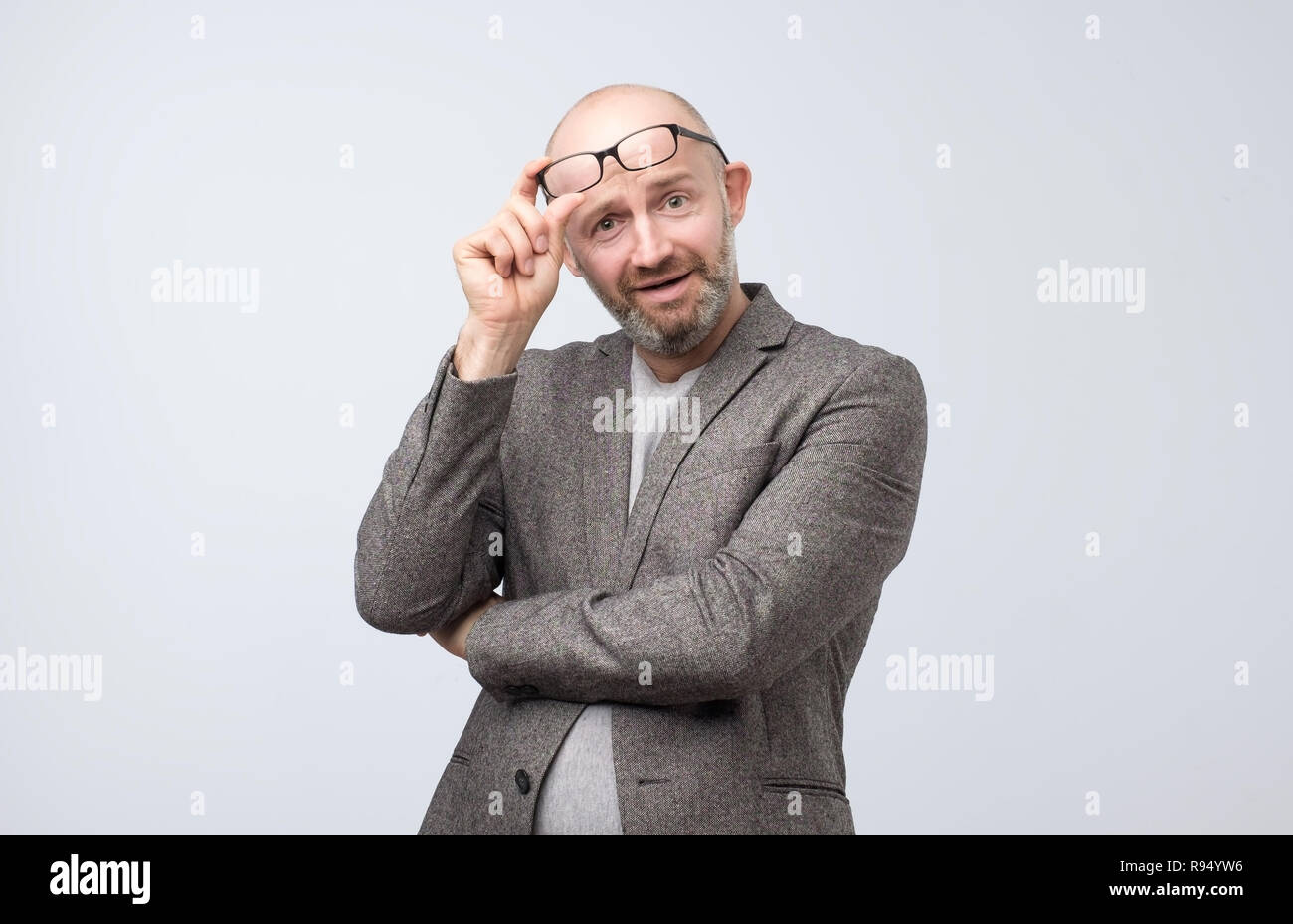 Portrait of curious mature man looking over glasses at camera Stock ...