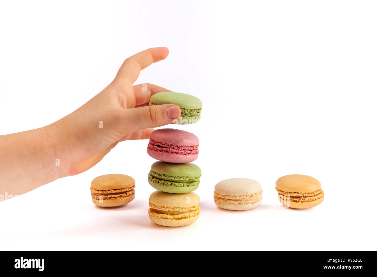 Little girl's hand building tower from French macarons on white ...