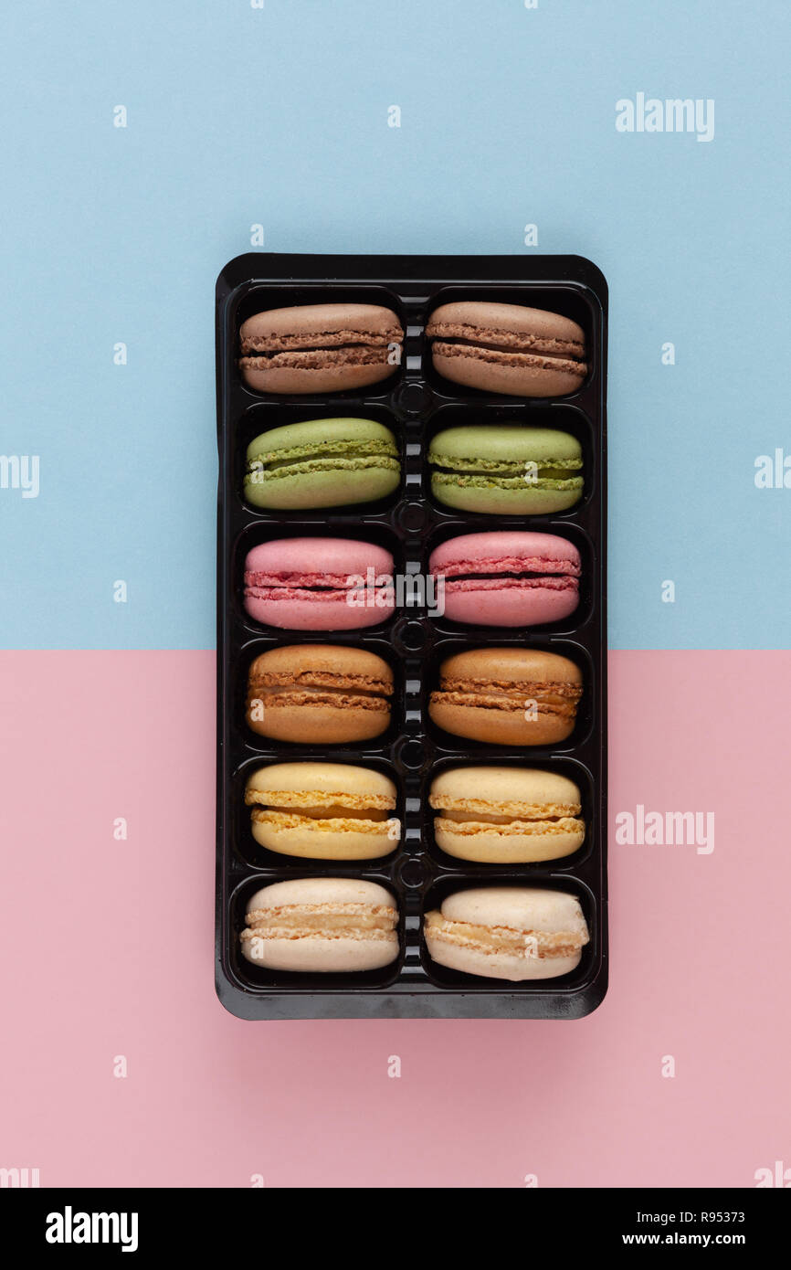 Colorful French macarons in package on pink-blue background - vertical ...