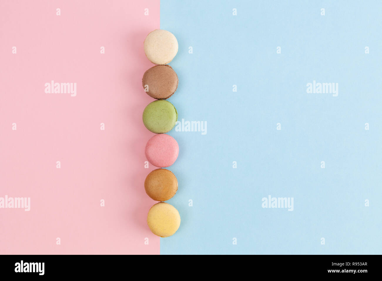 Row of colorful French macarons on pink-blue background with copy space ...