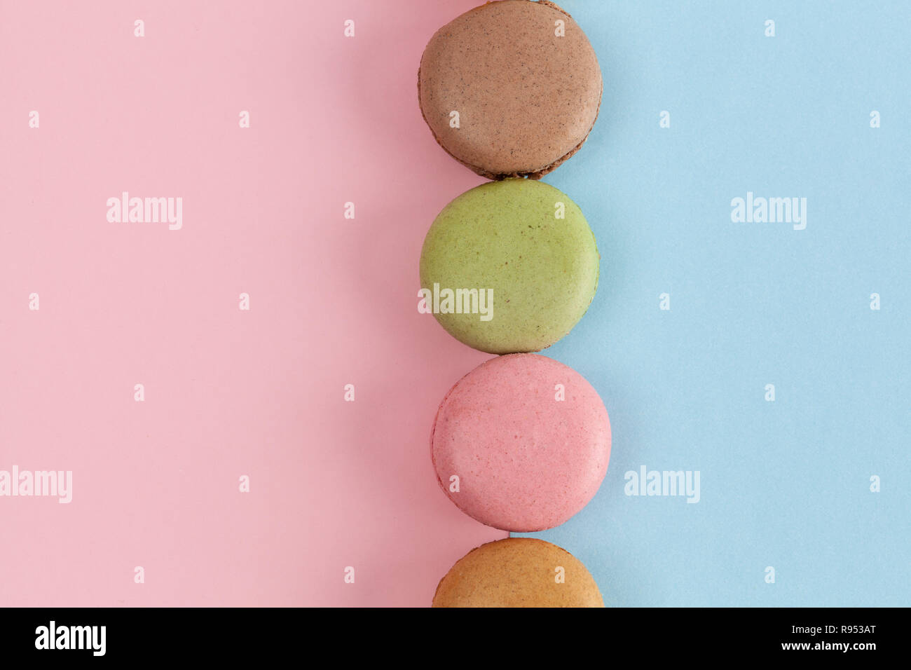 Row of macarons on pink-blue background closeup. Top view with copy ...