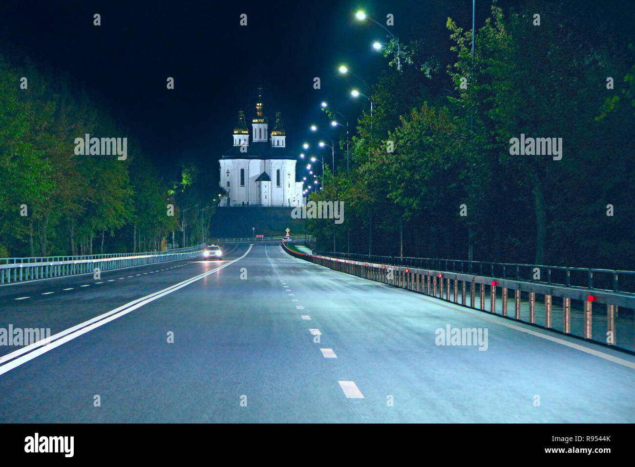 Night highway on background of beautiful church. Empty road with ...