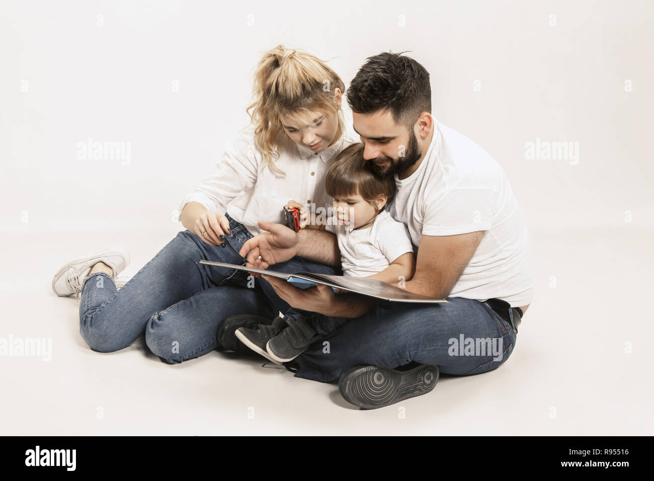 The happy family with kid sitting together and reading book isolated on ...