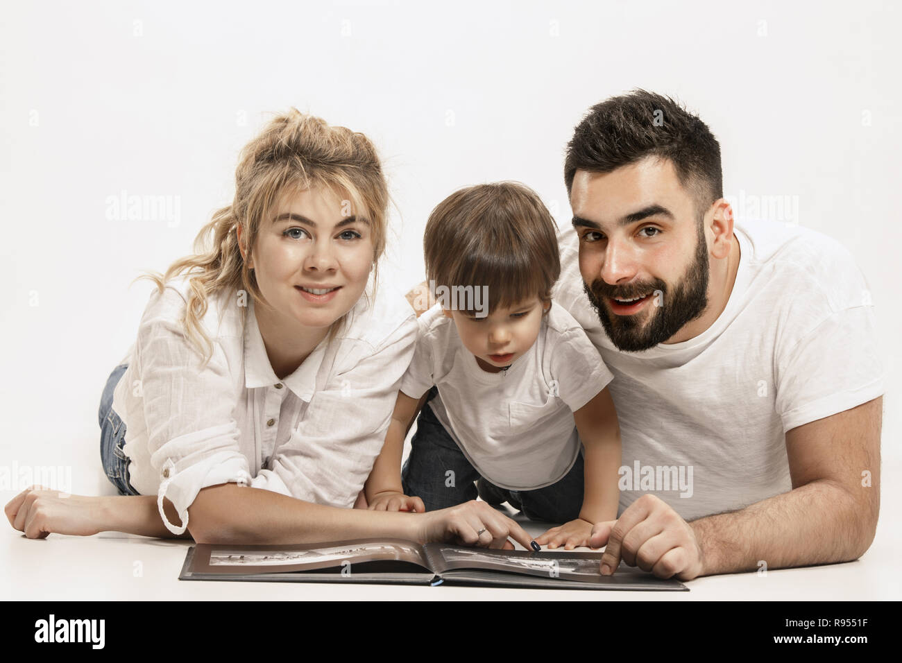 The happy family with kid sitting together and reading book isolated on ...