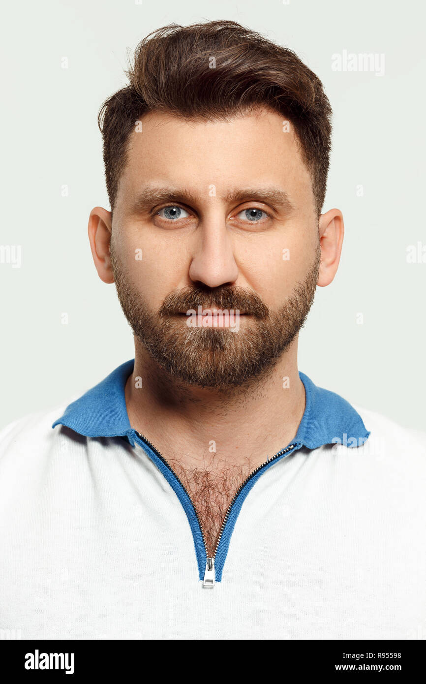 Serious man standing, looking at camera isolated on white studio ...