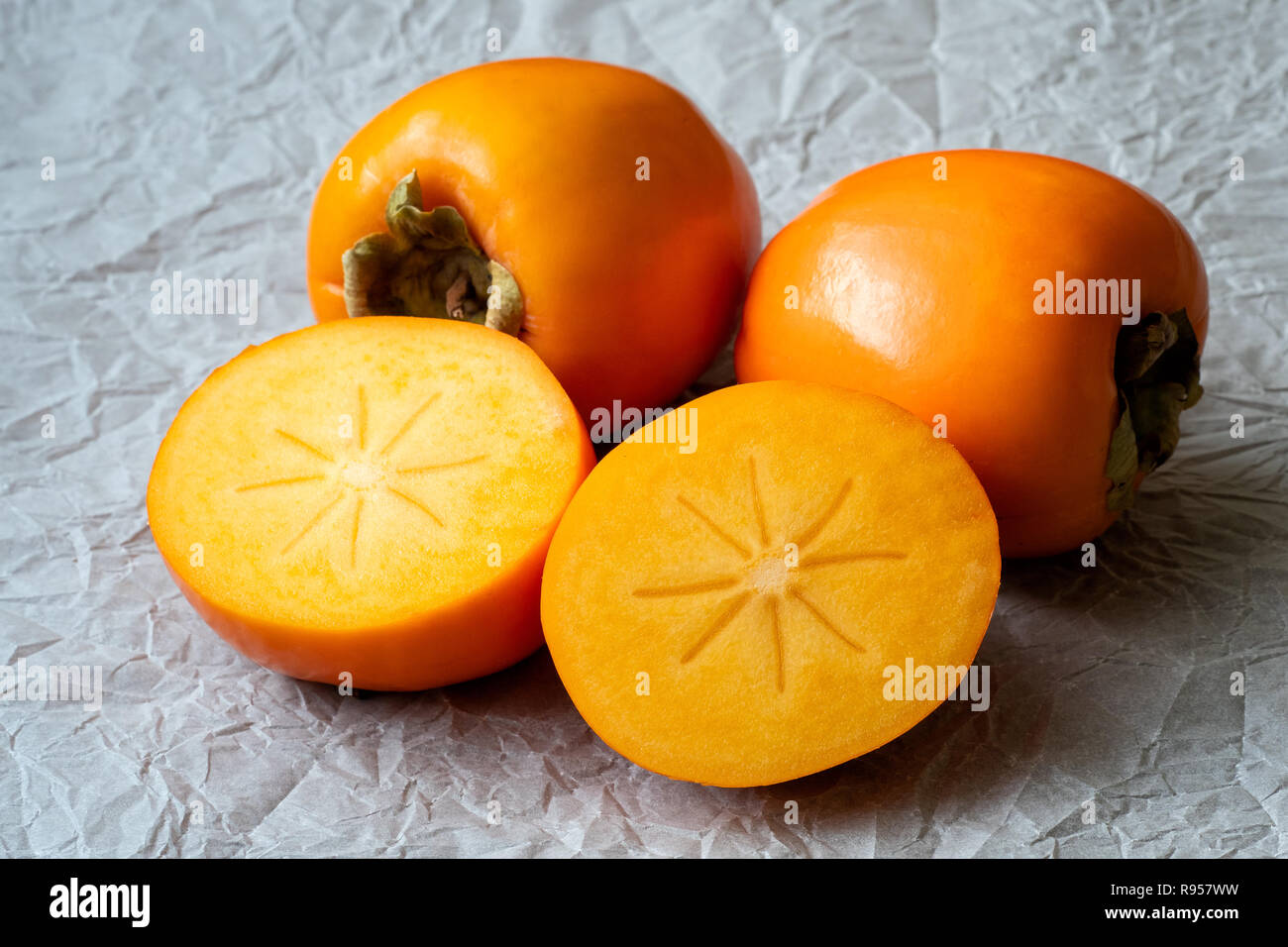 Whole and half of fresh ripe persimmons. Japanese persimmon (Diospyros ...
