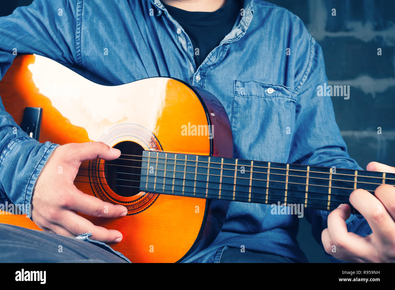Young man playing on a guitar. Yellow and orange musical instrument ...