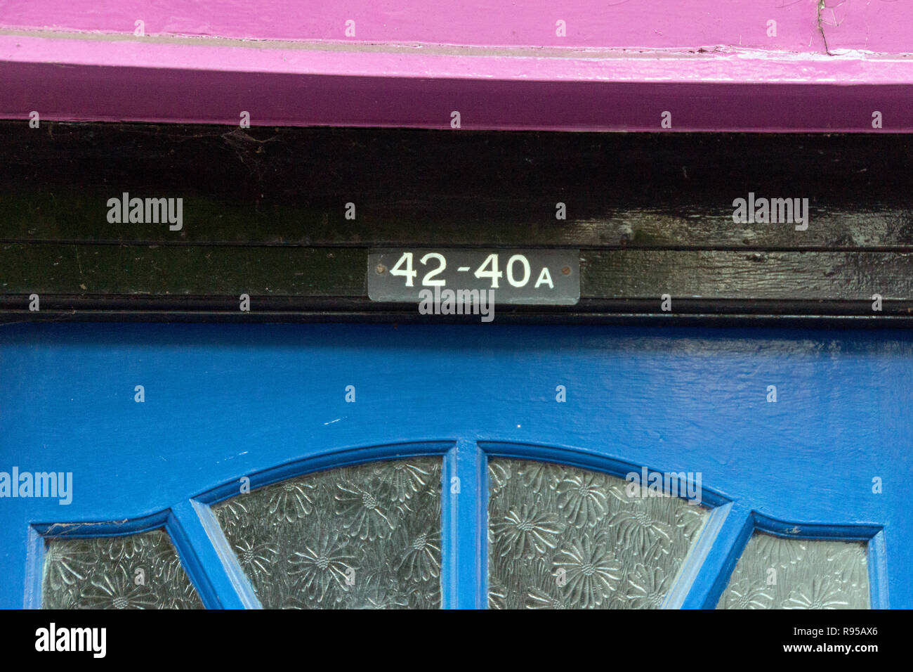 The house number 42 and 40A on a black, blue, and purple painted door ...