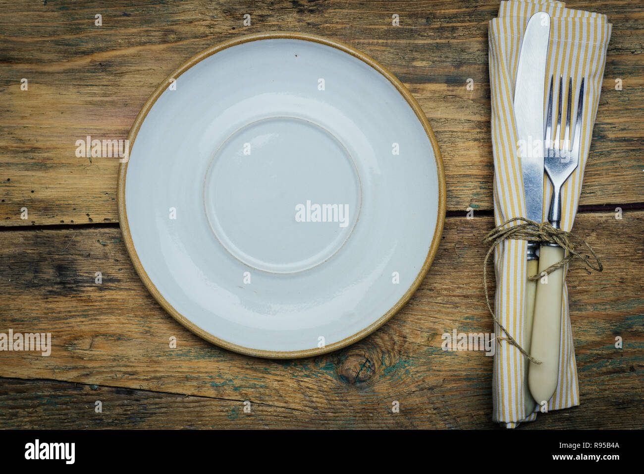 Empty white rustic plate on old wooden background with knife, fork and ...