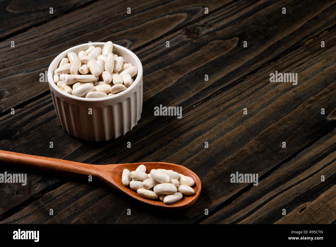 White beans in pot. Wooden black background Stock Photo - Alamy