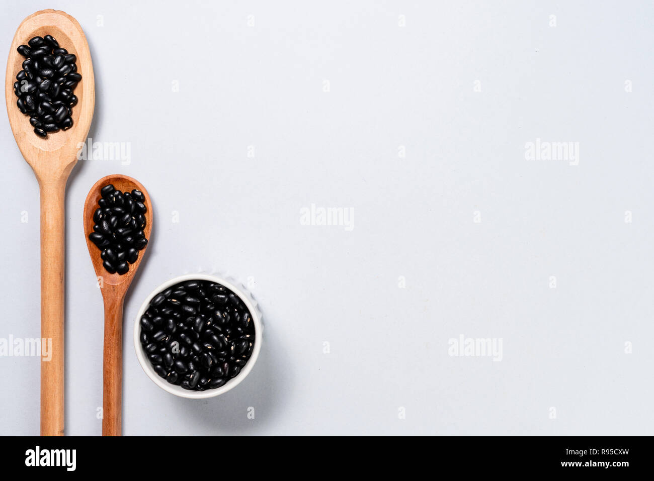 Wooden spoon and pot with black beans. Background with space for text ...