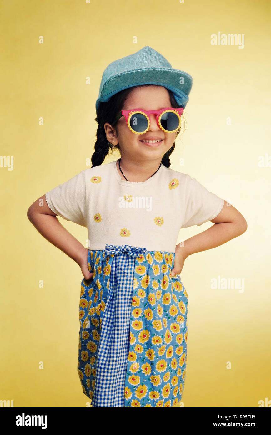 Girl wearing fancy glasses, cap, frock, yellow background Stock Photo ...