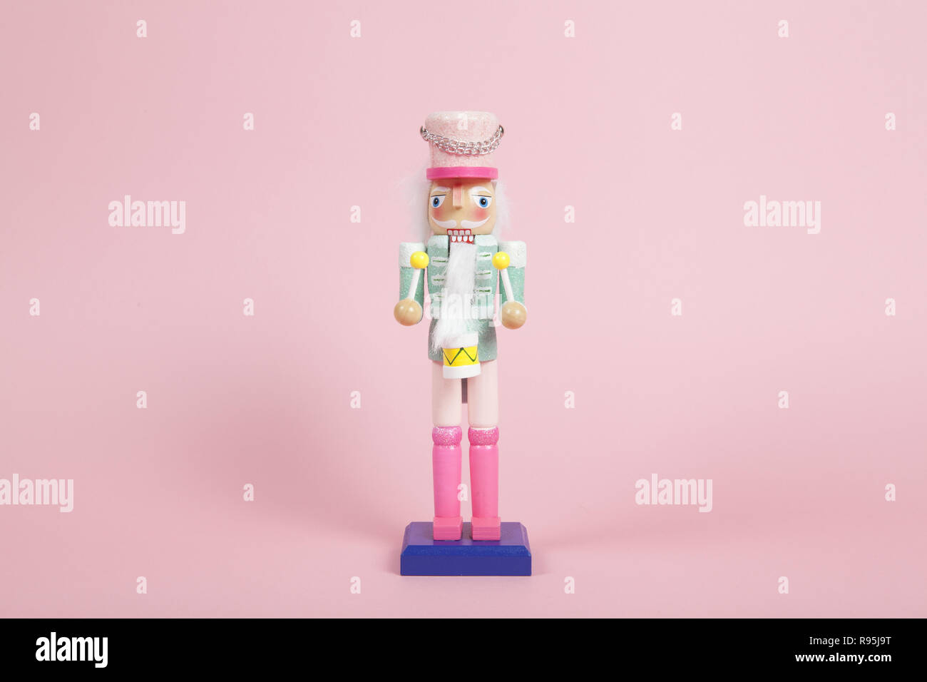 wood nutcracker figurine placed on a pink background. Color harmony ...